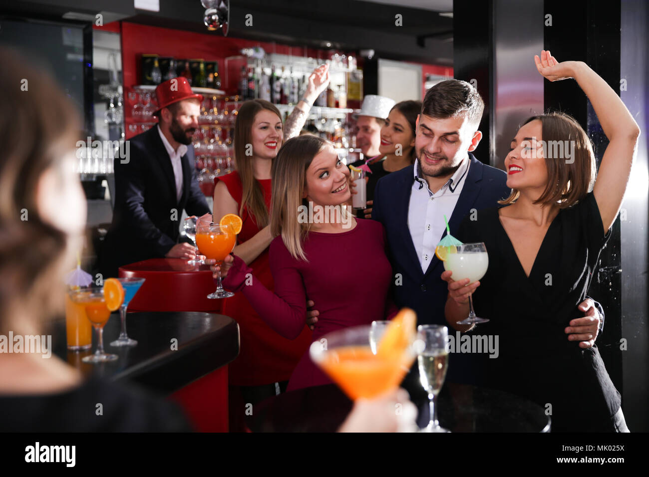 Happy young man with female friends enjoying cocktail party in bar ...