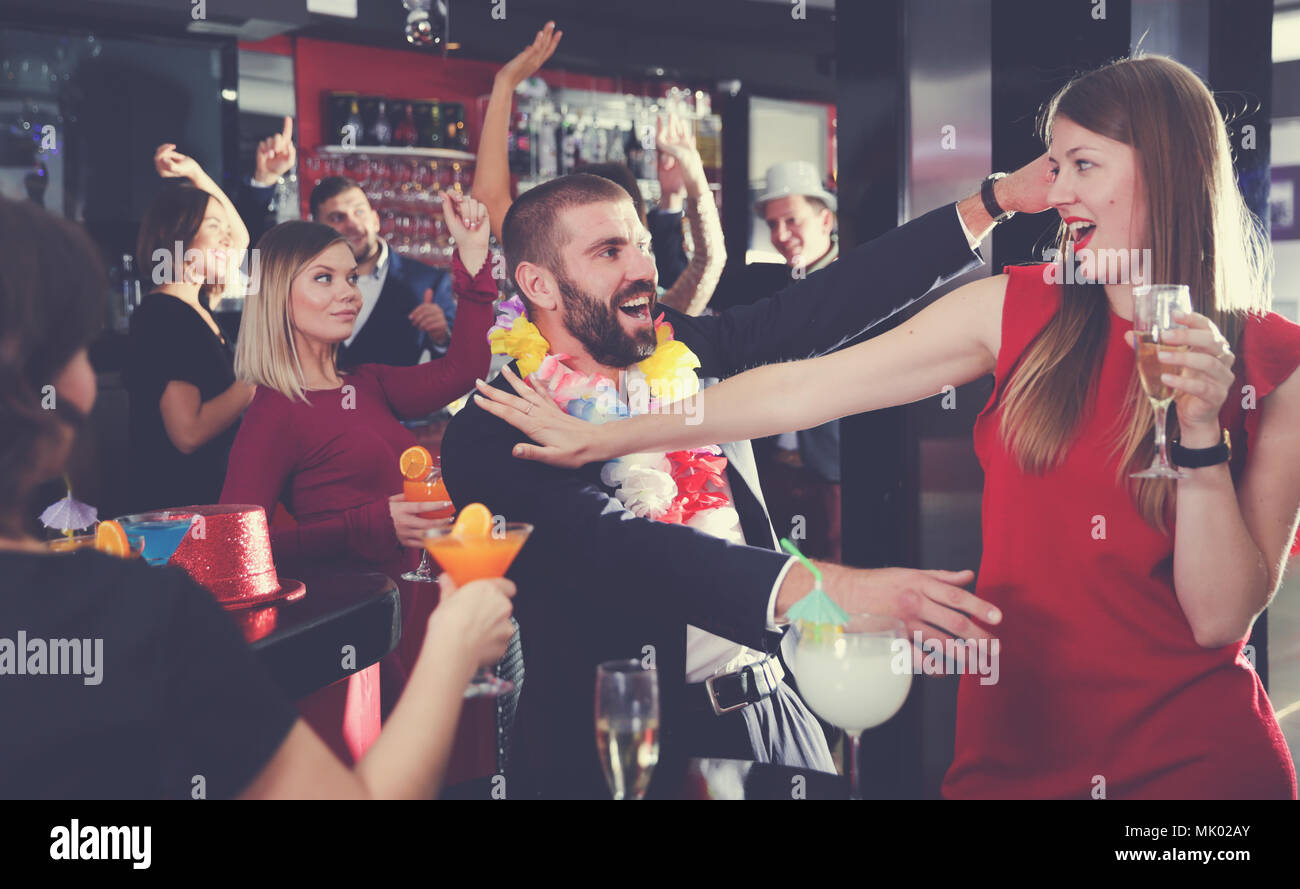 Young man with female colleague enjoying corporate party in Hawaiian ...