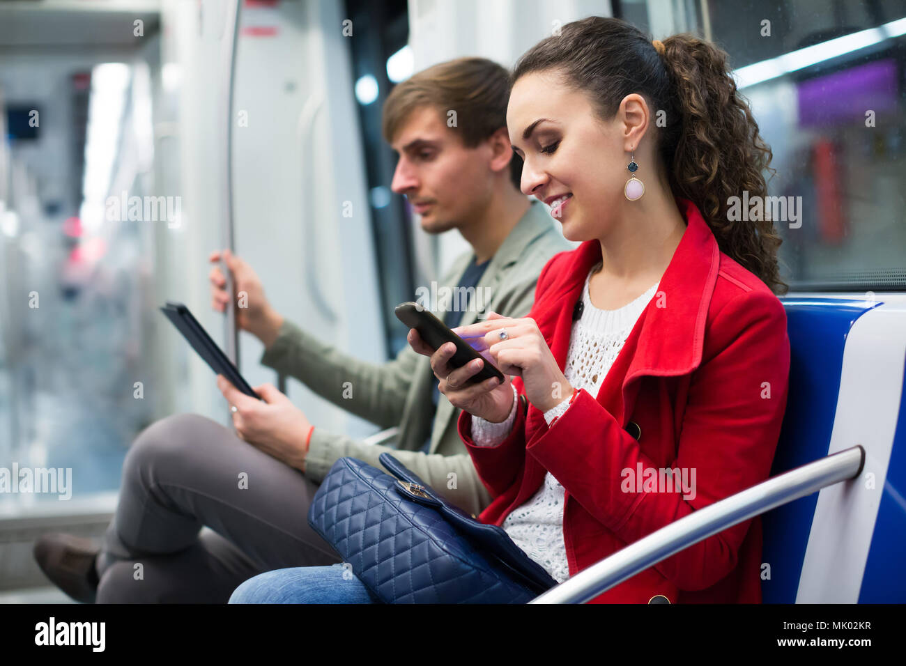 Positive people reading smartphone and e-book in metro car Stock Photo ...