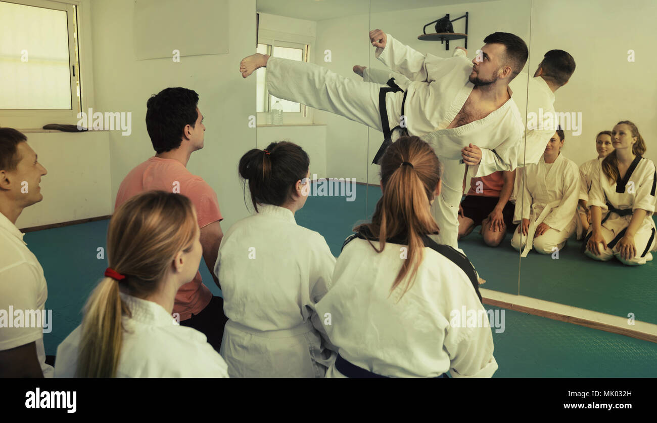 Young male coach showing new moves to adults in karate class Stock ...