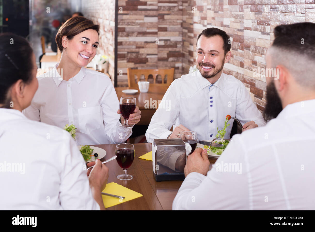 group of riant friends eating at restaurant table and chatting Stock ...