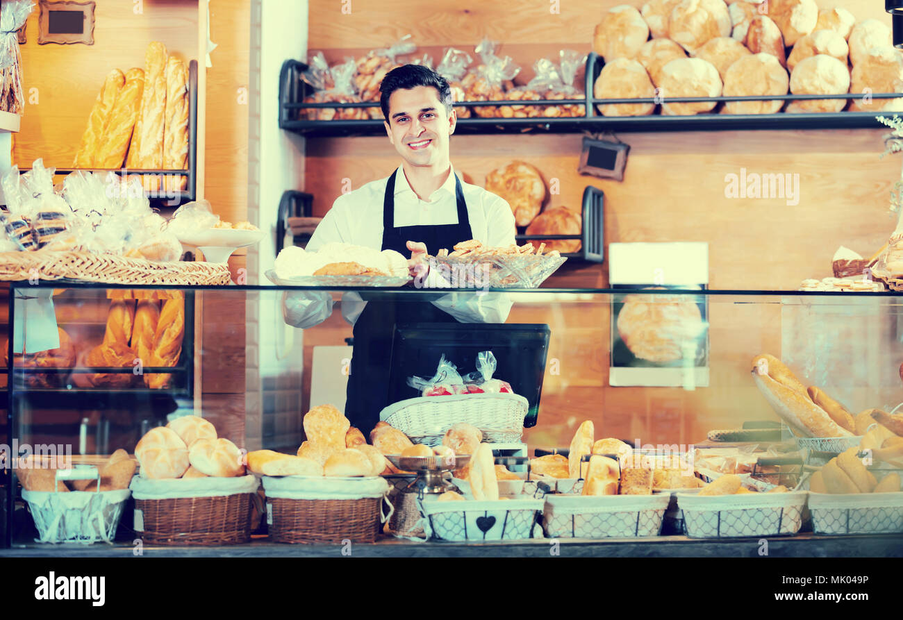 Portrait of positive smiling man at bakery display with pastry Stock ...