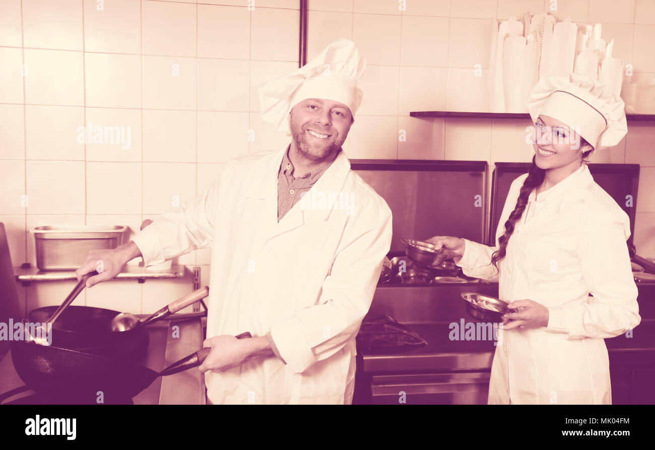 Positive professional chef and cook working at take-away restaurant ...