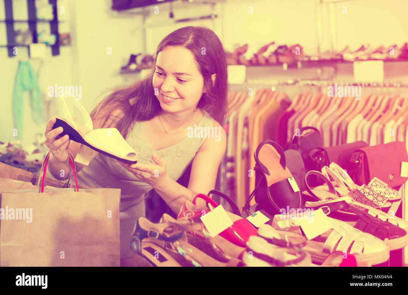 Portrait of smiling female customer selecting shoes in footgear center ...