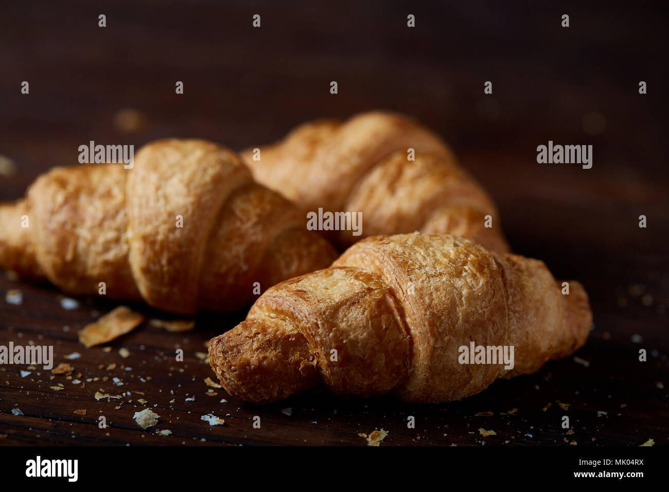 Tasty buttery croissants on an old wooden table, close-up, selective focus, shallow depth of ...