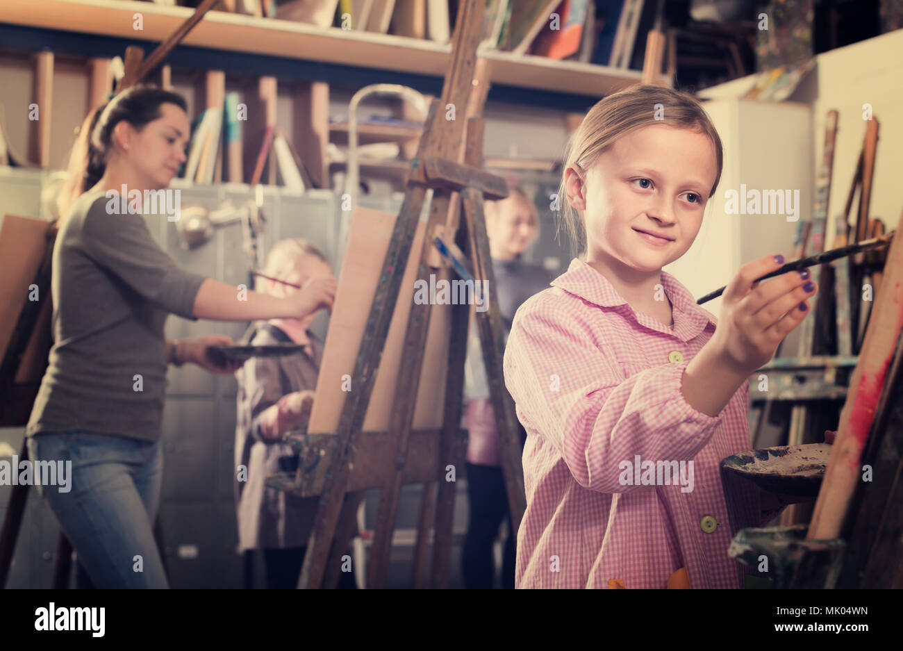Smiling italian schoolgirls diligently training their painting skills ...
