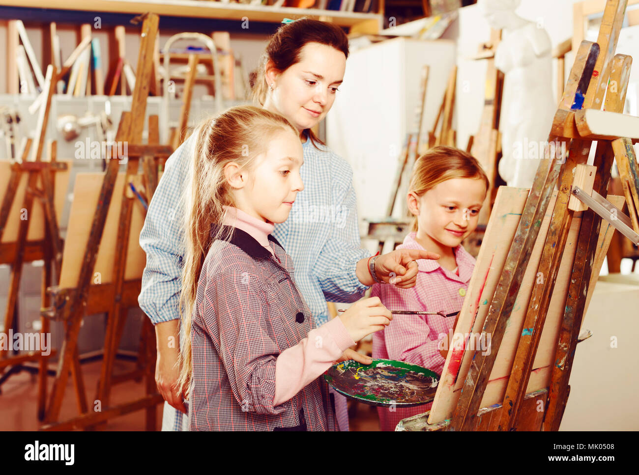 Smiling teacher giving workshop session during painting class at art ...