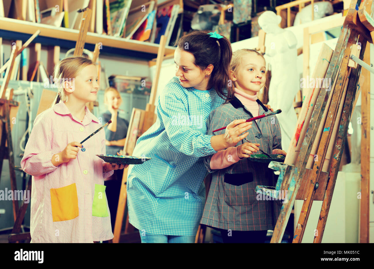 Glad female teachers assisting students during painting class at art ...