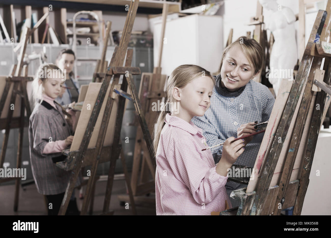 Portrait female teacher helping girl during painting class at art ...