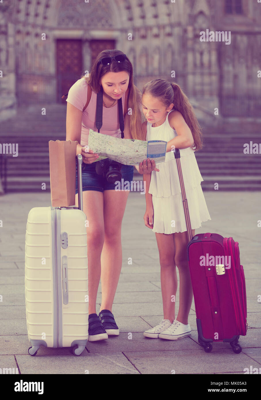 Portrait of positive woman and daughter tourists looking for ...