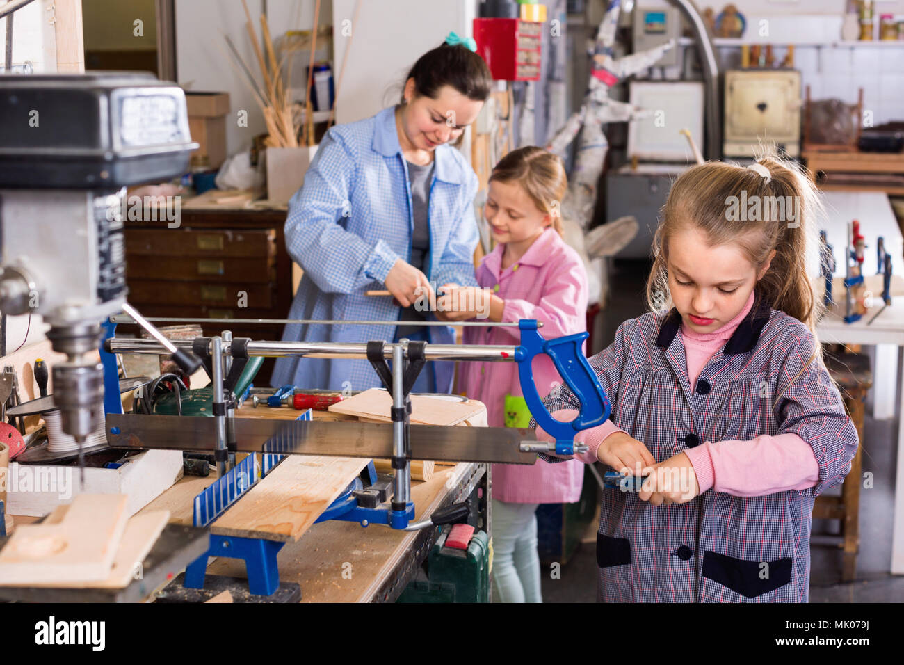 Smiling positive schoolgirls learning to carve wood during arts and ...