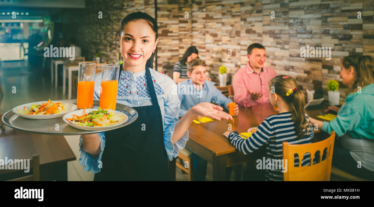 young waitress warmly welcoming guests to comfortable family cafe Stock ...