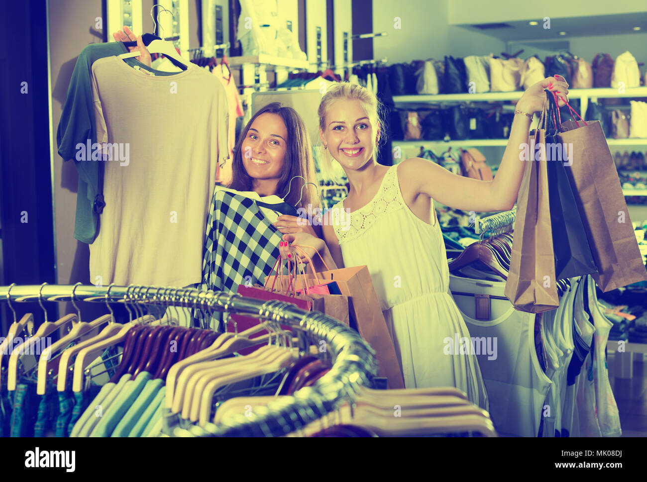Two young smiling girls shopping clothes in fashion department Stock ...