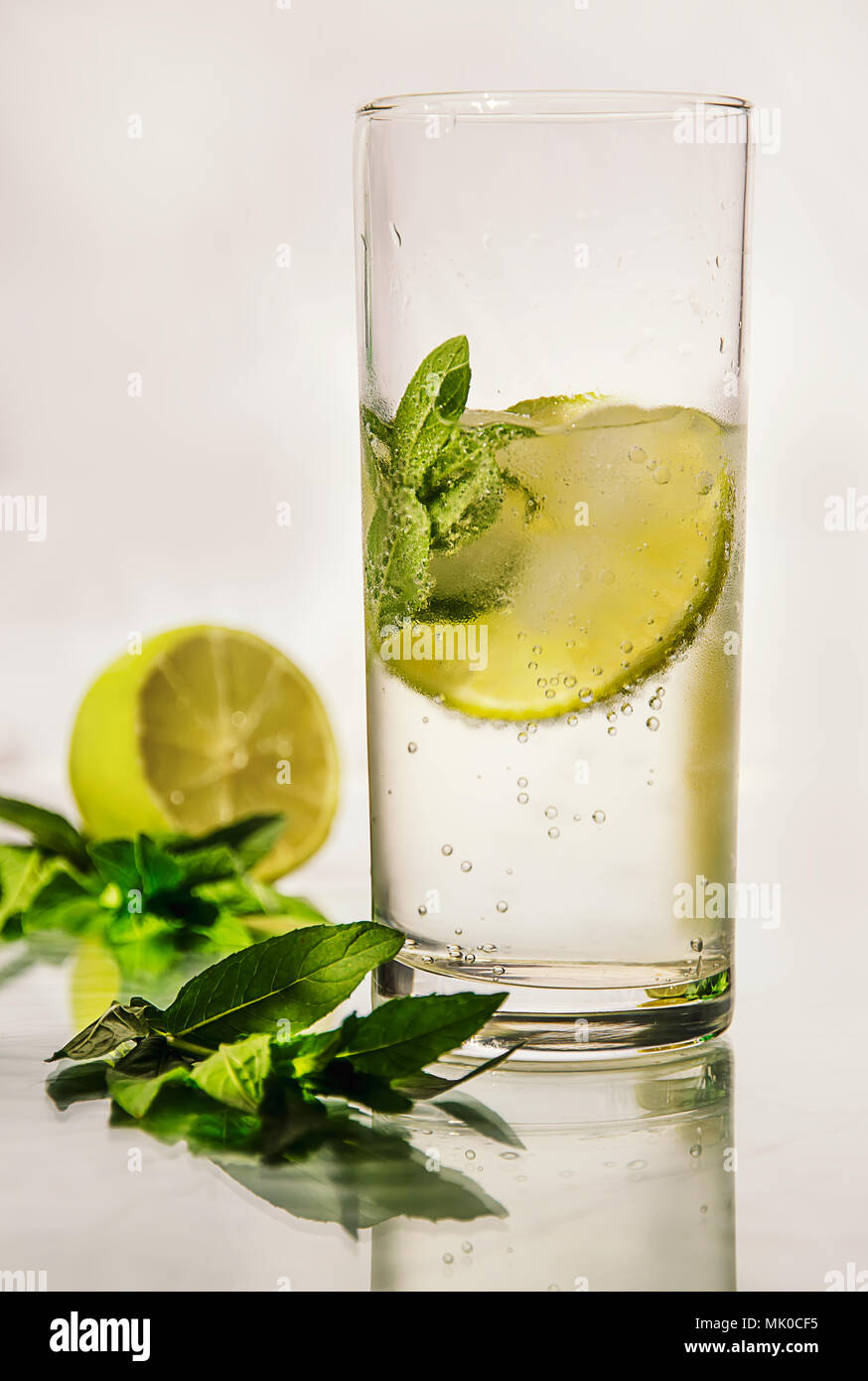 Cold fresh water with bubbles, lime, ice and mint in glass. Healthy ...