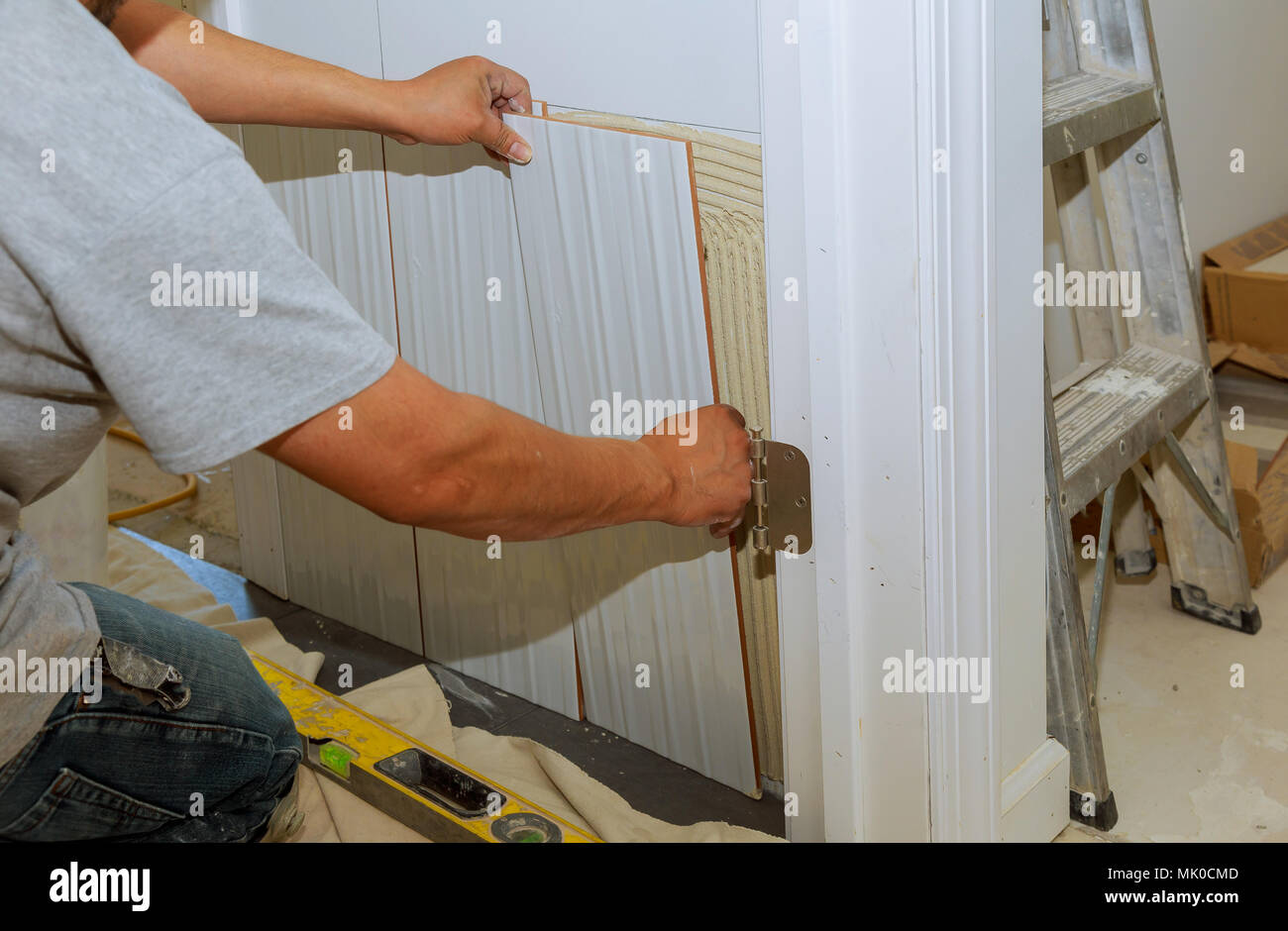 Ceramic Tiles. Tiler placing ceramic wall tile in position over ...