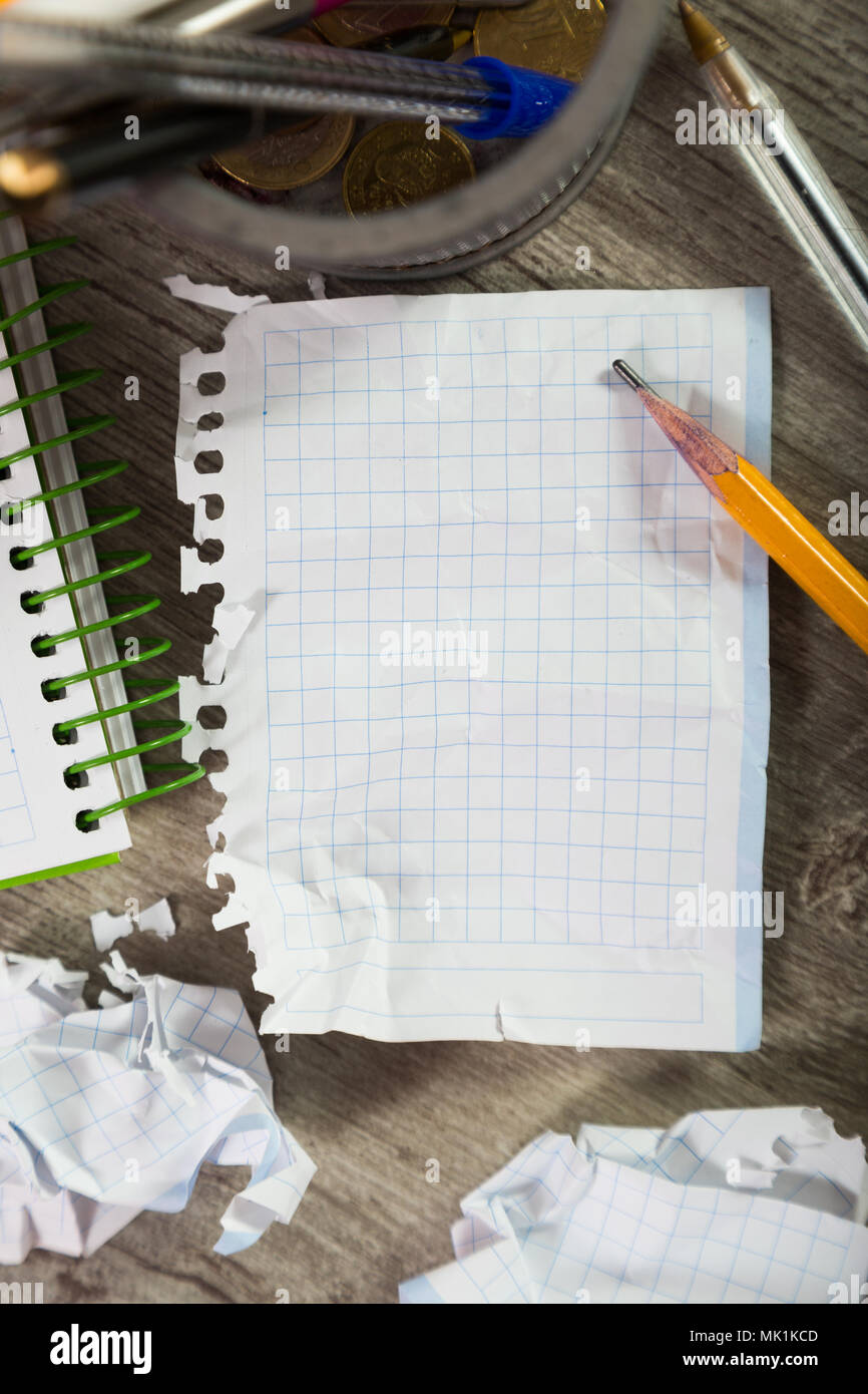 Torn crumpled notebook sheet in cage surrounded by stationery Stock ...