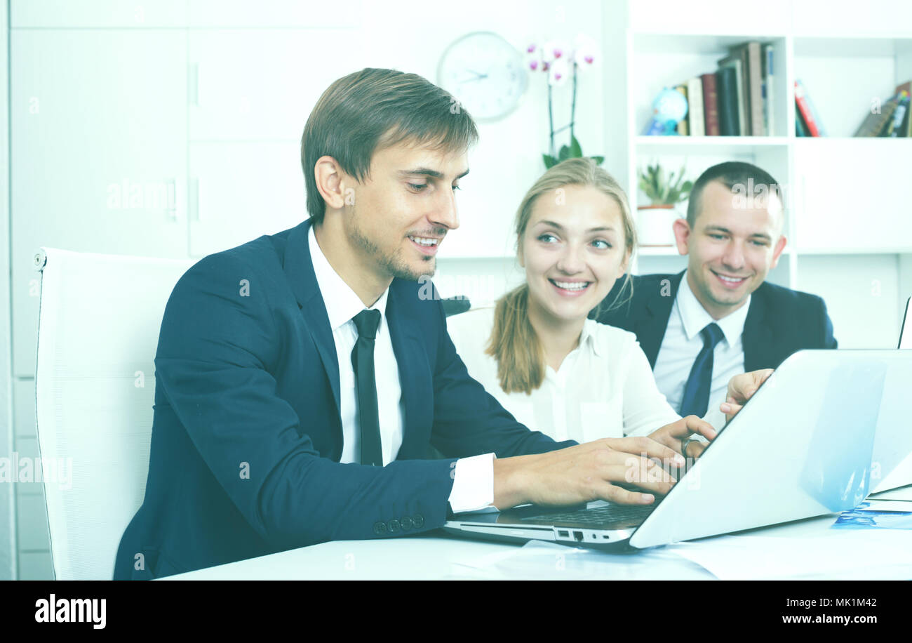 three young business male and female assistants in formalwear working ...