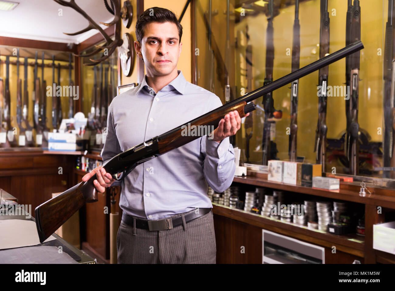 Active male hunter choosing shotgun in store with hunt equipment Stock ...