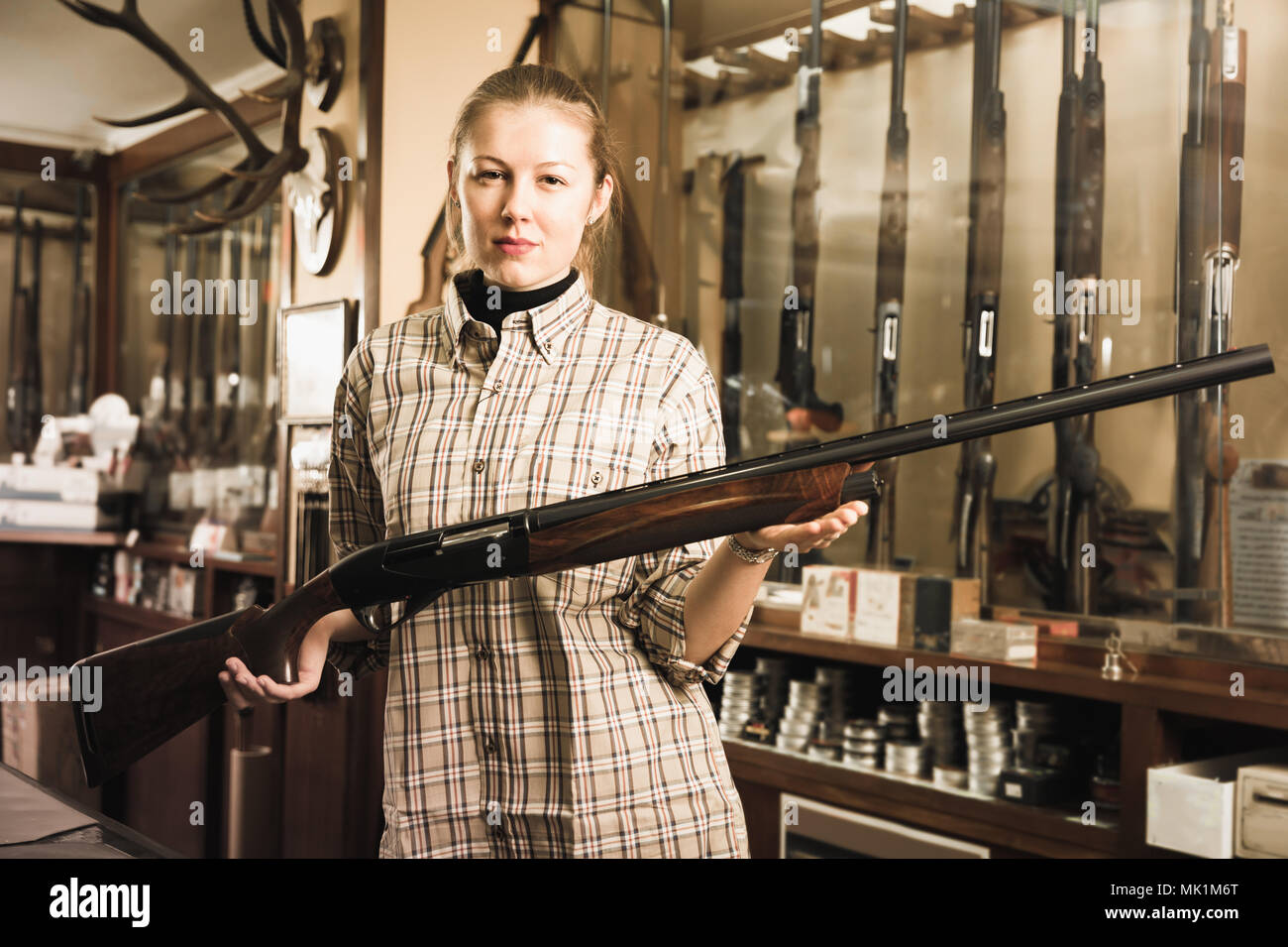 Positive female in hunting shop with rifle in hands Stock Photo - Alamy