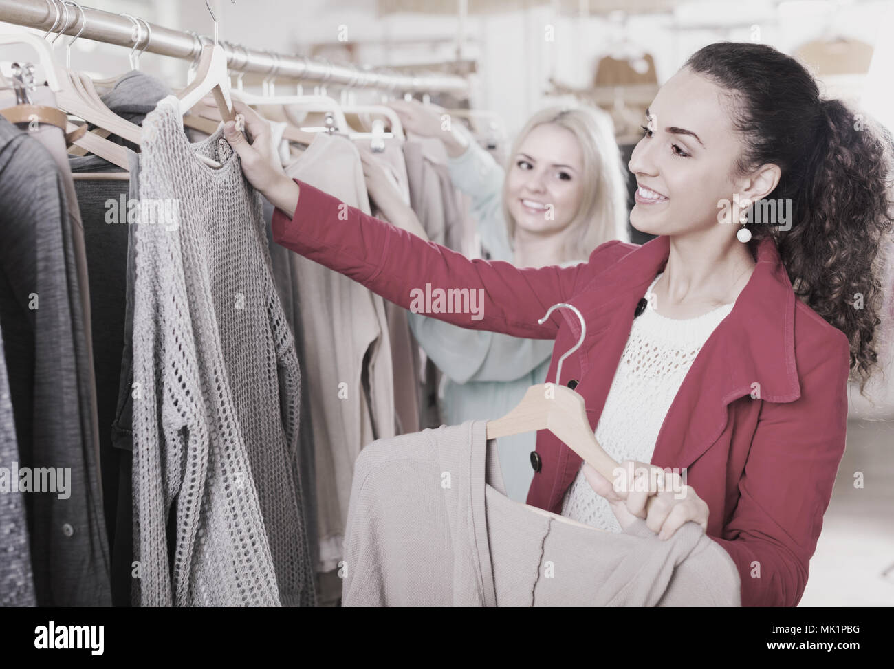Two cheerful young women choosing basic garments at clothing store ...