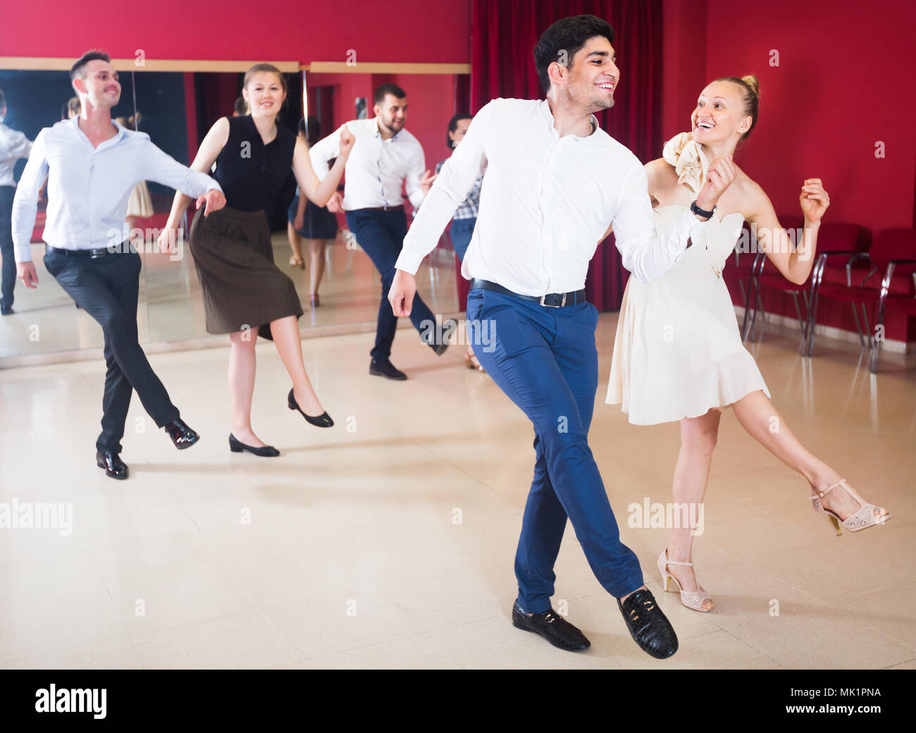 Young people practicing vigorous jive movements in dance class Stock ...