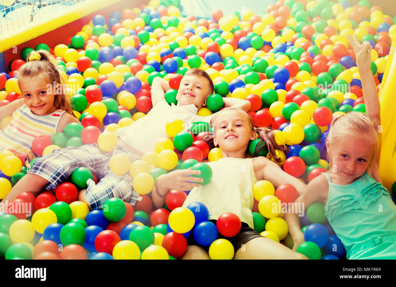 cheerful little kids playing together with multicolored plastic balls ...