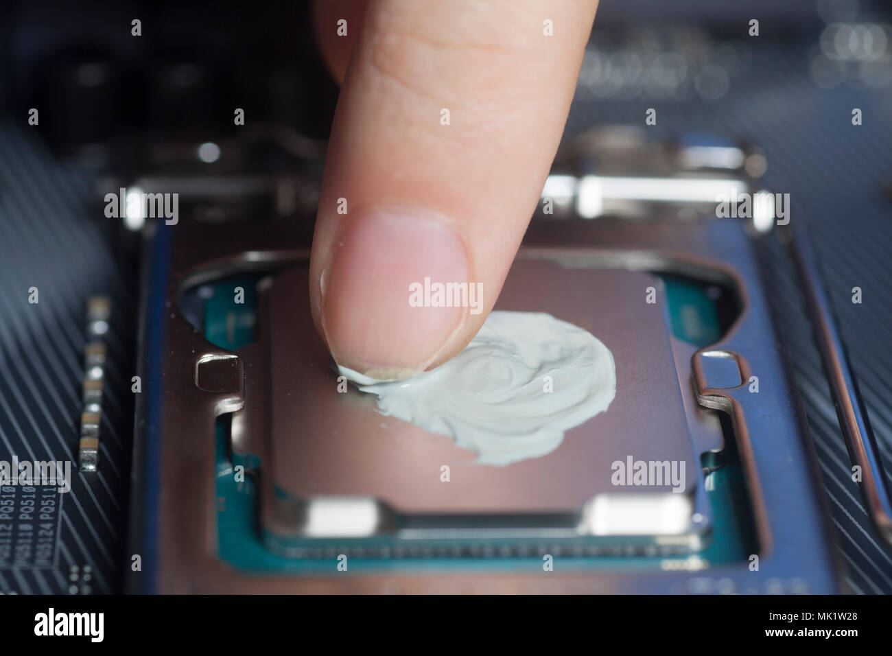 Applying thermal paste with finger in CPU on motherboard close up Stock ...