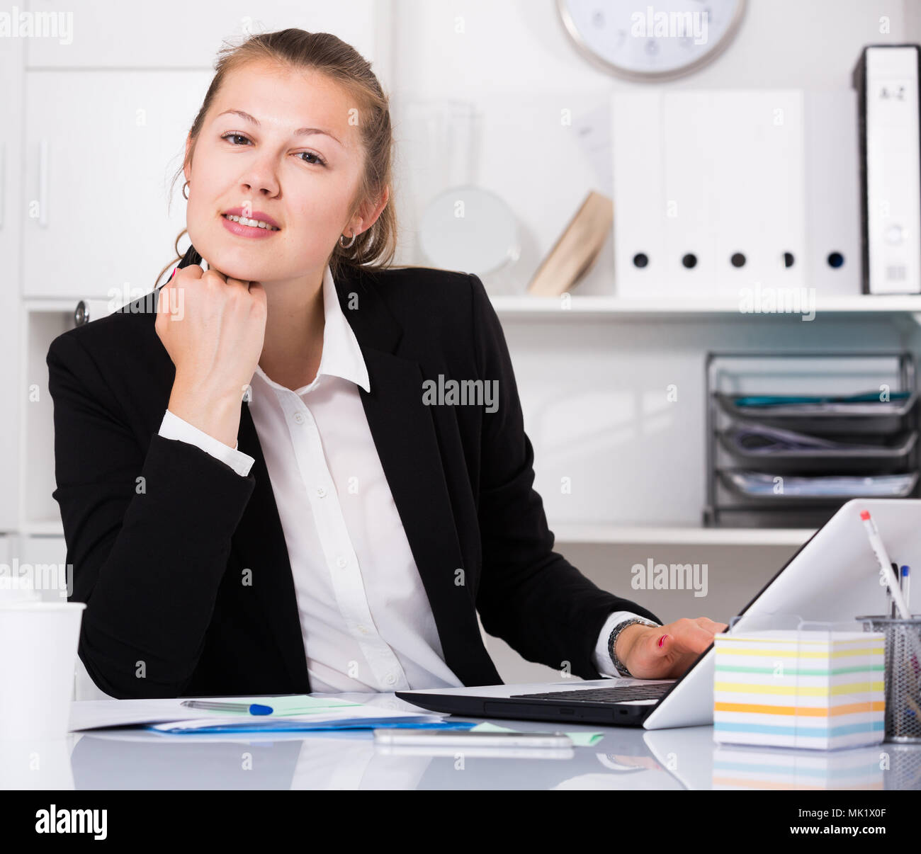 Businesswoman is posing while working behind laptop in the office Stock ...