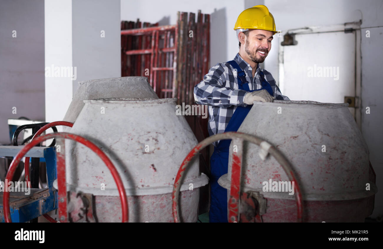 Smiling male worker using concrete mixer for construction work at ...