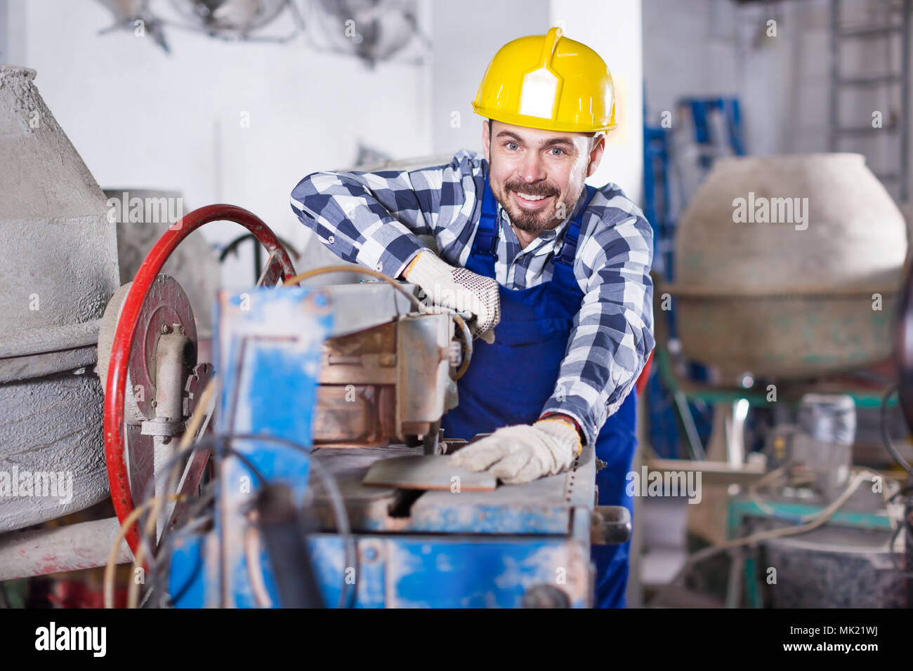 Smiling working man practicing his skills with disk saw machine at the ...