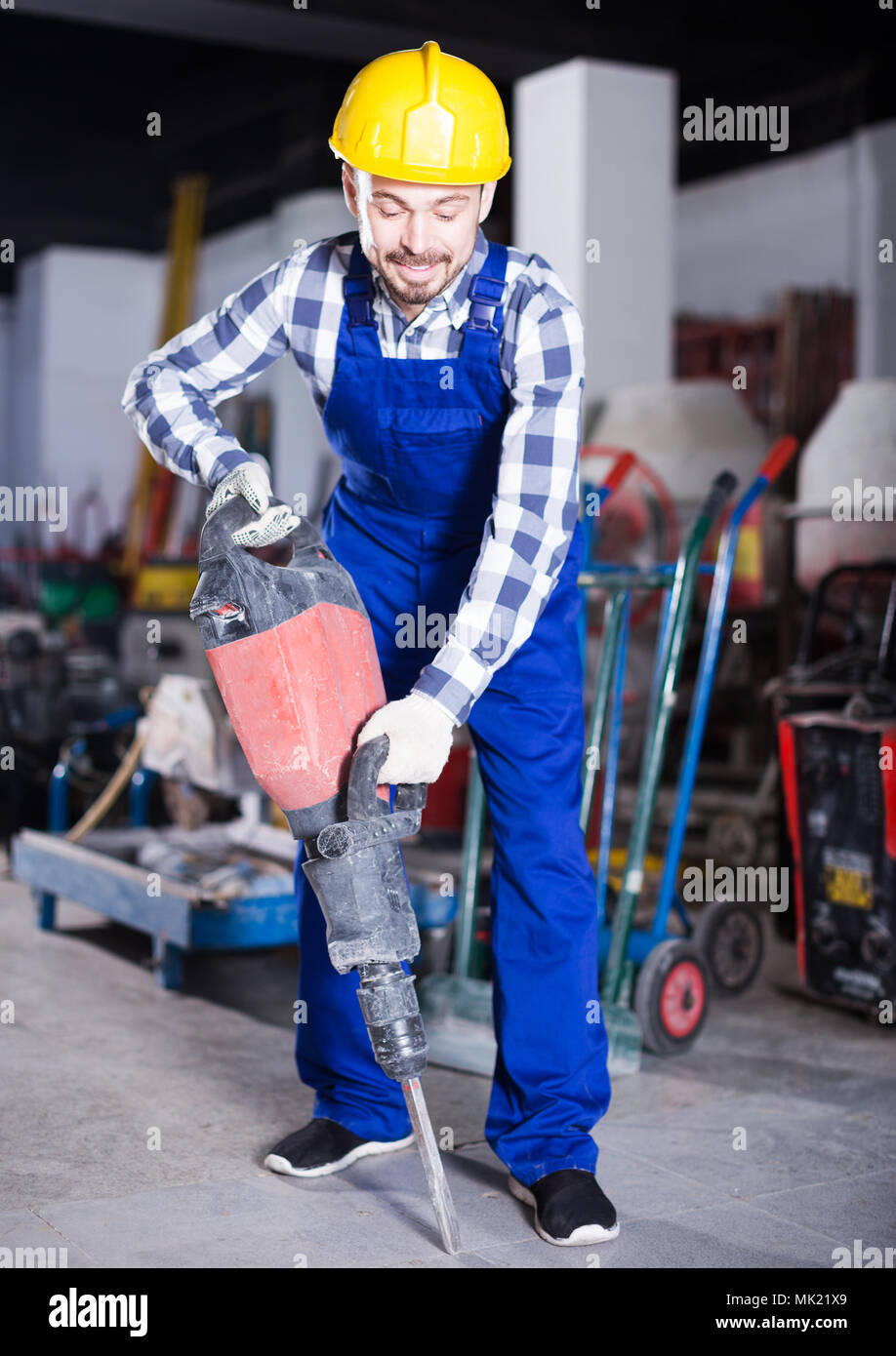 Positive male worker starting to work with demolition hammer at ...