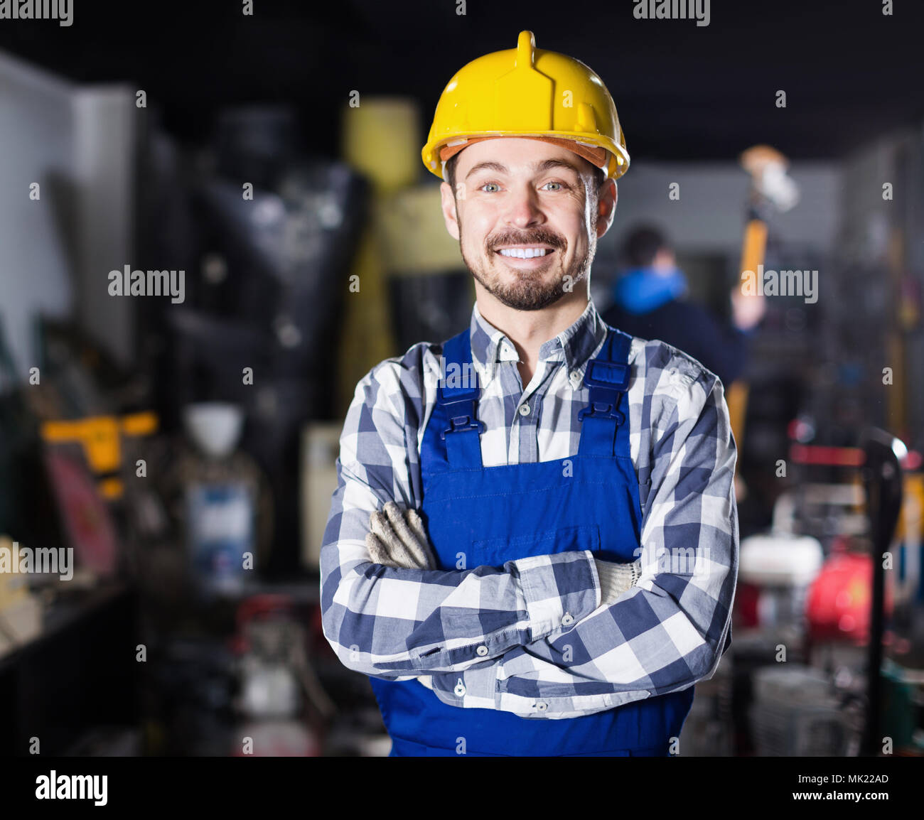Young smiling worker displaying his workplace and tools at workshop ...