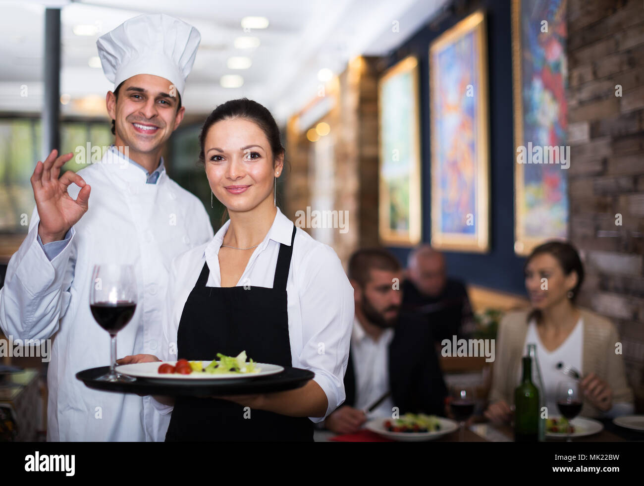 Glad young waitress with cook chef standing in restaurant Stock Photo ...