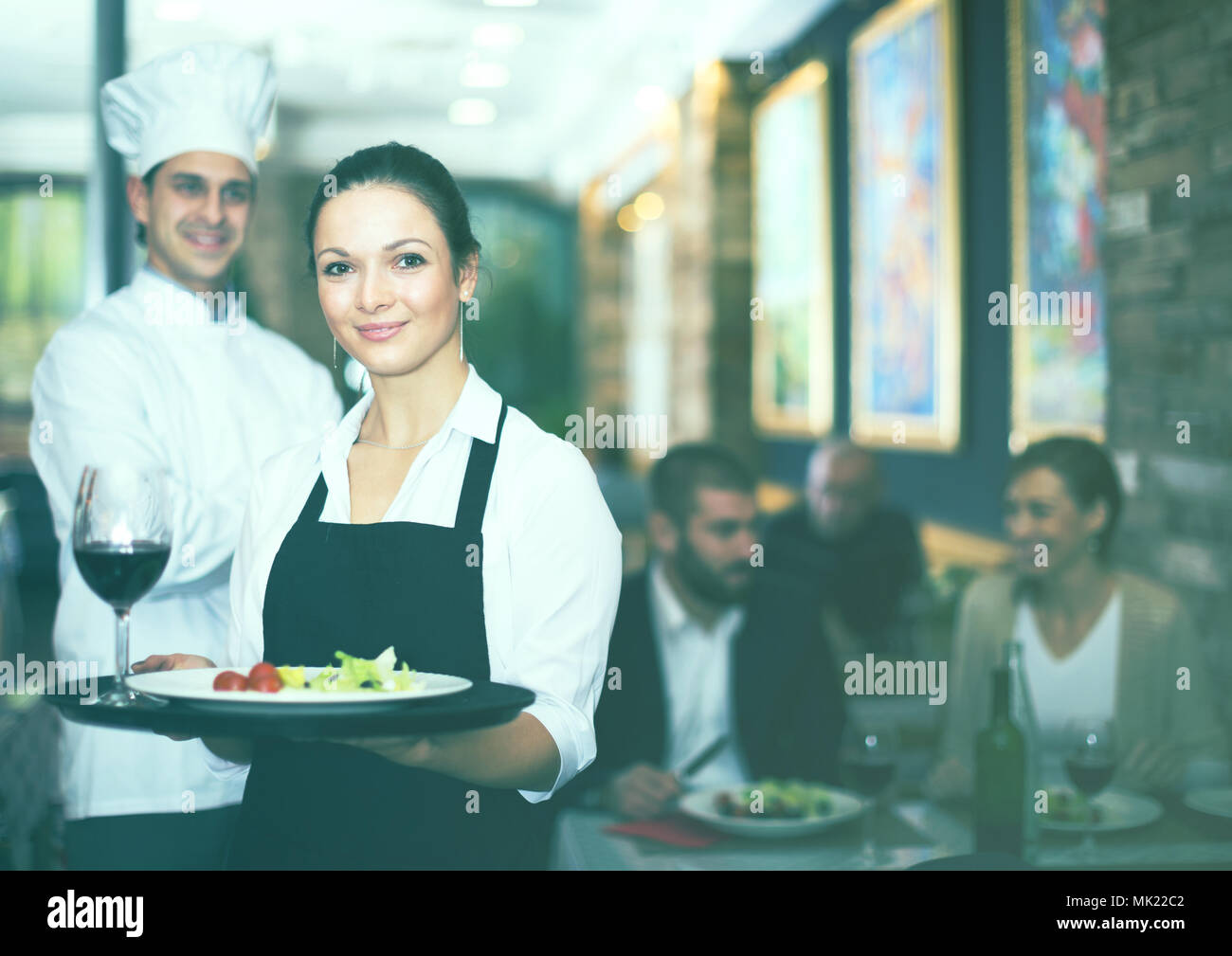 Portrait of smiling young waitress with cook chef standing in ...