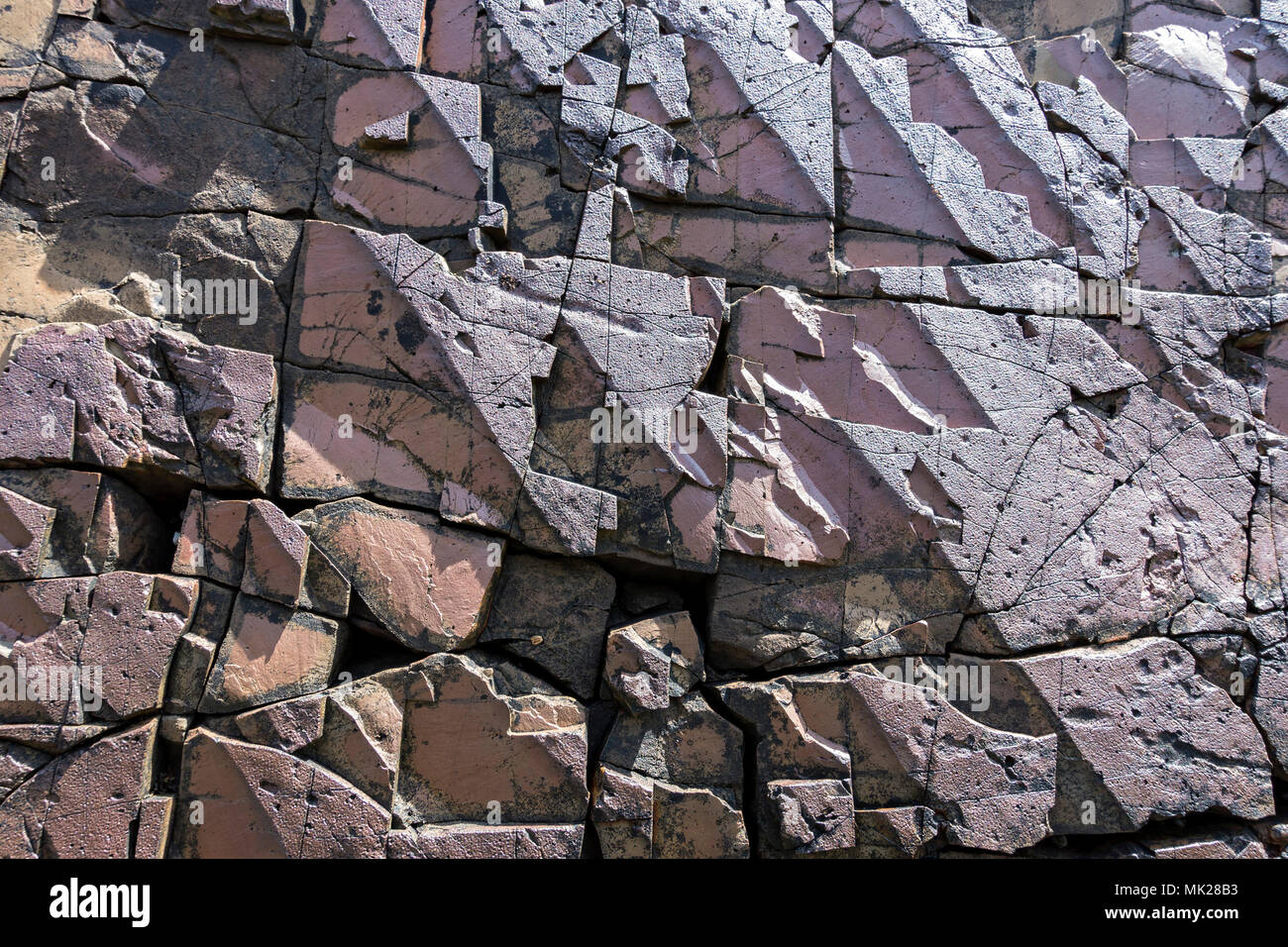 Closeup of geometric fractured rock surface of vertical volcanic dyke ...