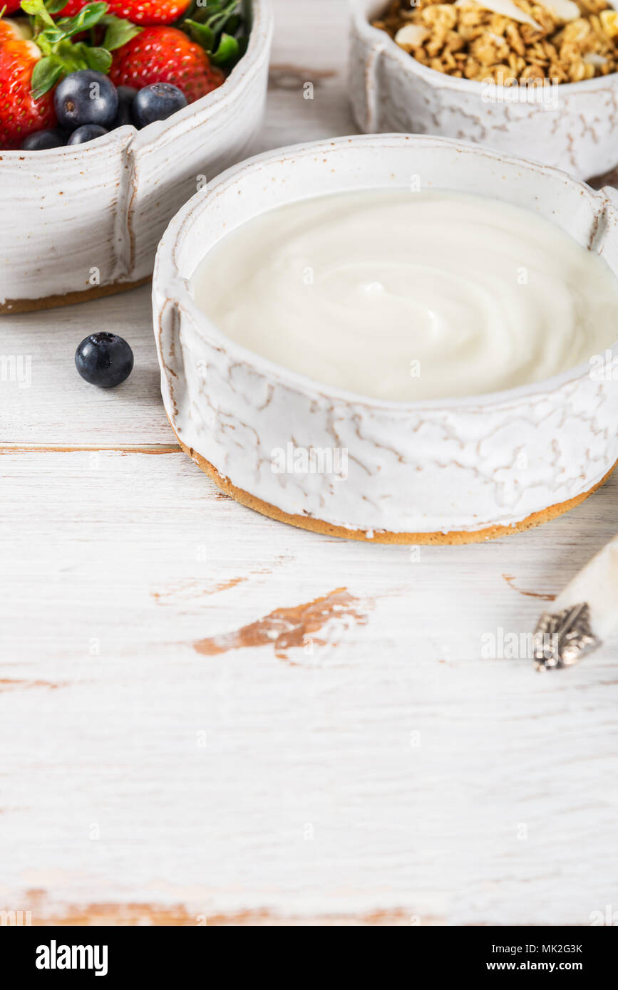 Bowl of natural yogurt with granola and fresh berries on wooden ...