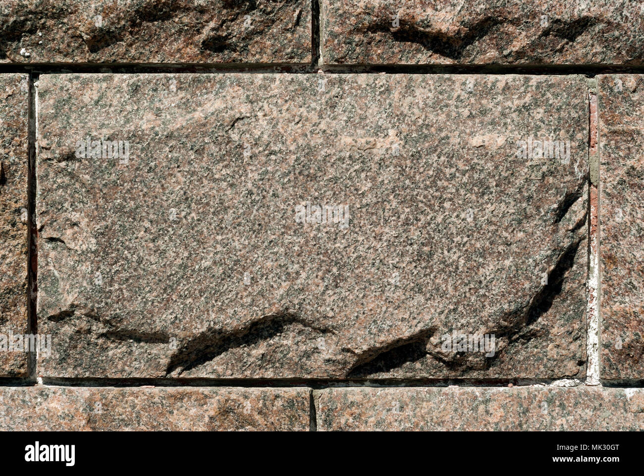 rough granite rectangular block in the composition of masonry wall ...