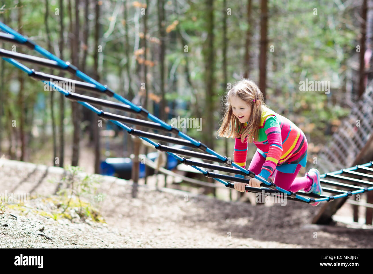 Child in forest adventure park. Kids climb on high rope trail. Agility ...