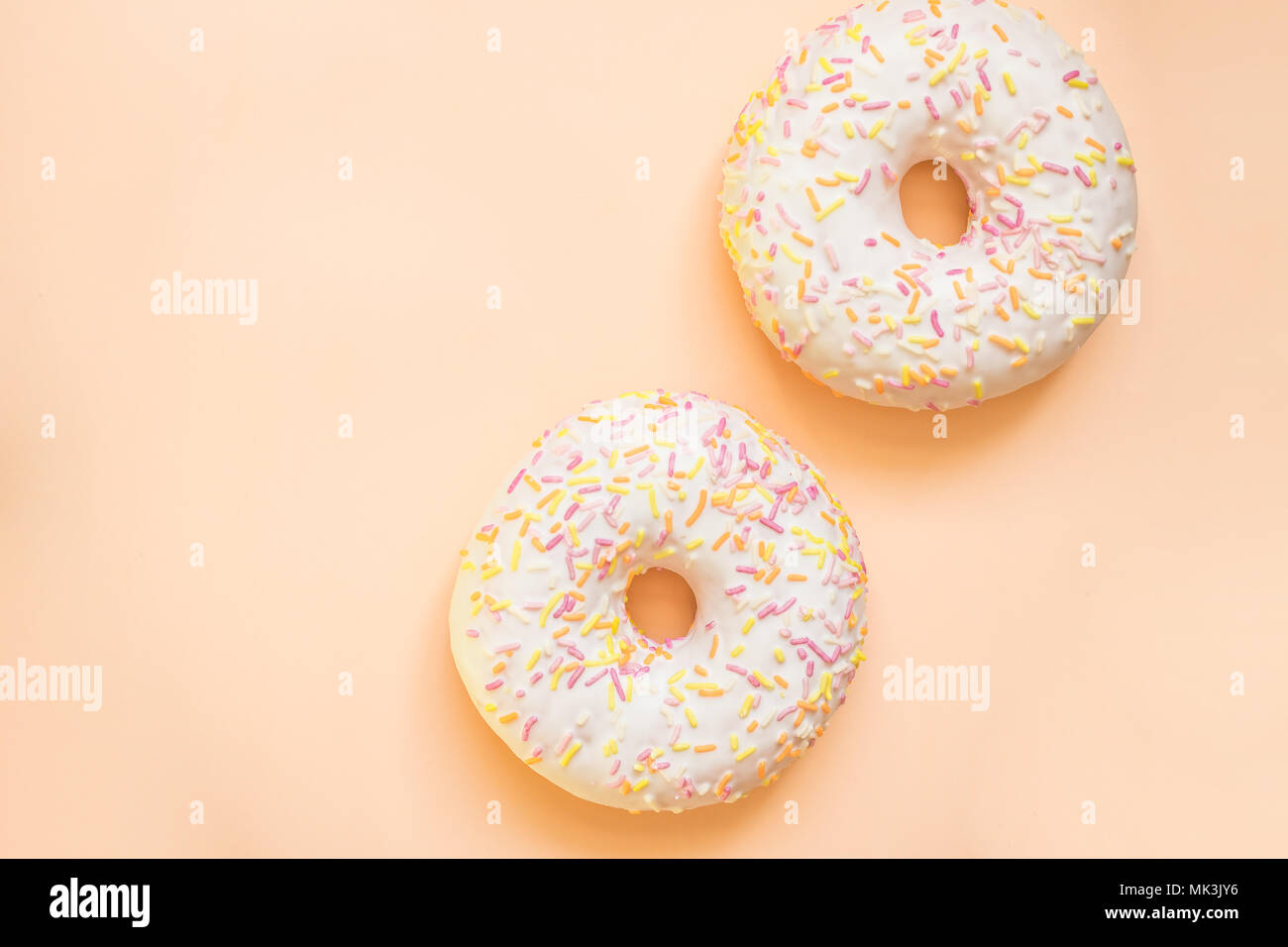 Donut with white icing colored topping, isolated on yellow background ...
