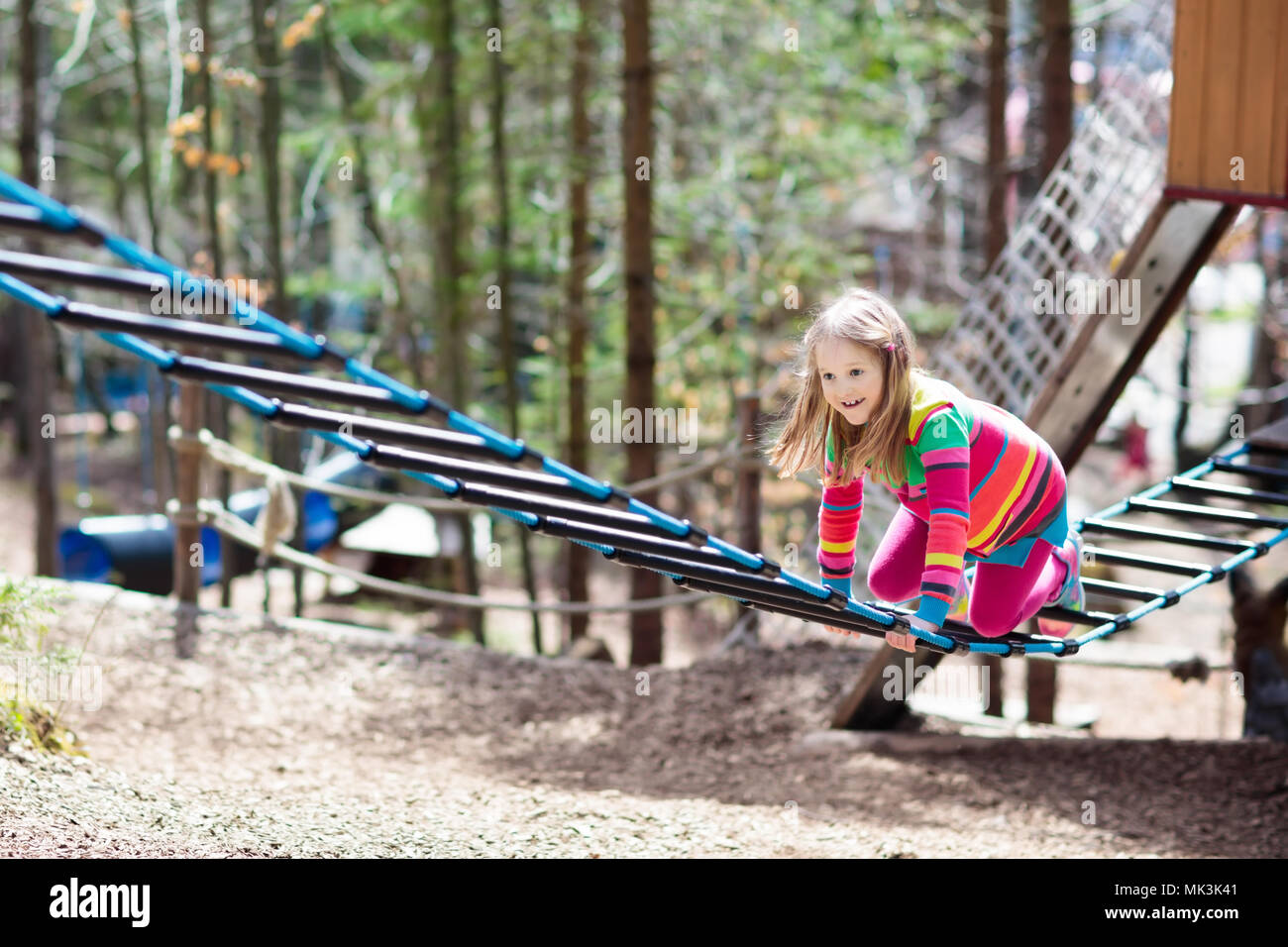 Child in forest adventure park. Kids climb on high rope trail. Agility ...