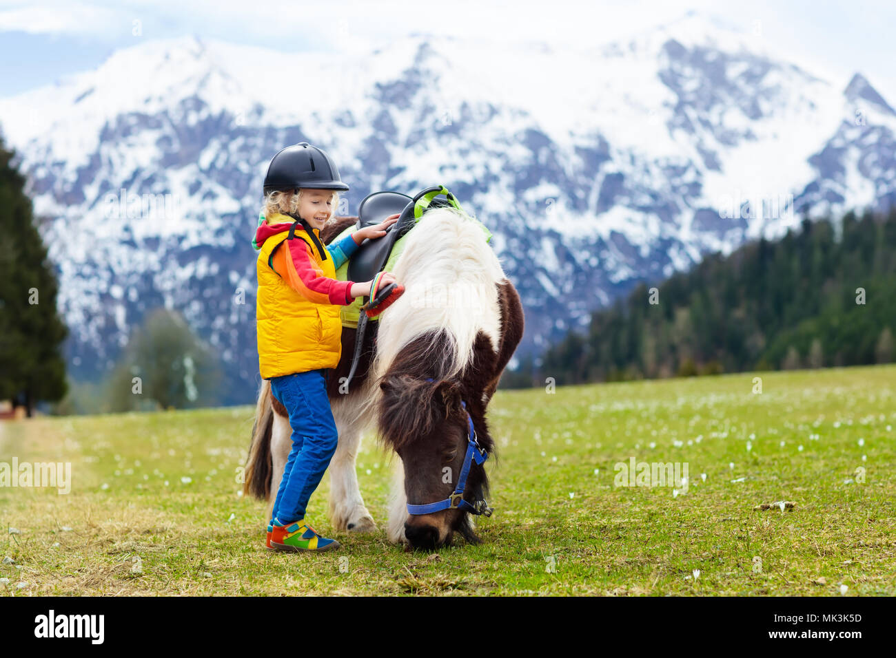 Kids riding pony in the Alps mountains. Family spring vacation on horse ...