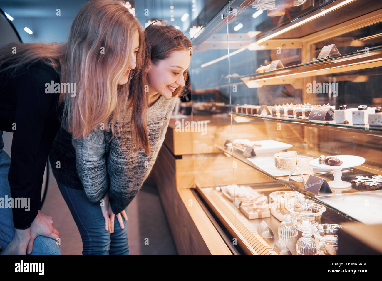 Two happy attractive girls choosing delicious ganaches, praline and ...