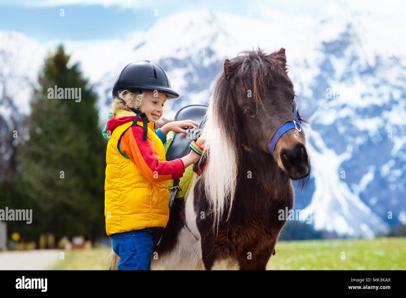Kids riding pony in the Alps mountains. Family spring vacation on horse ...