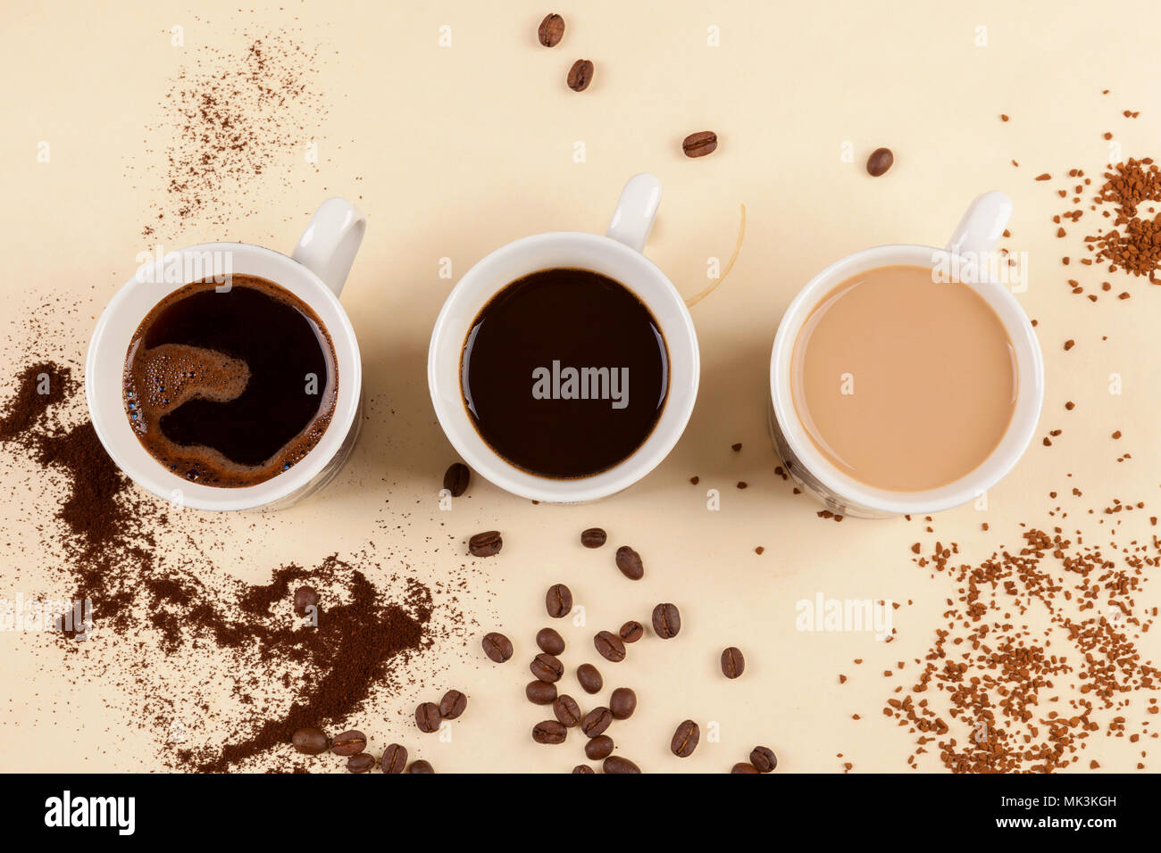 Three cups of coffe with ground and instant coffee and roasted beans ...