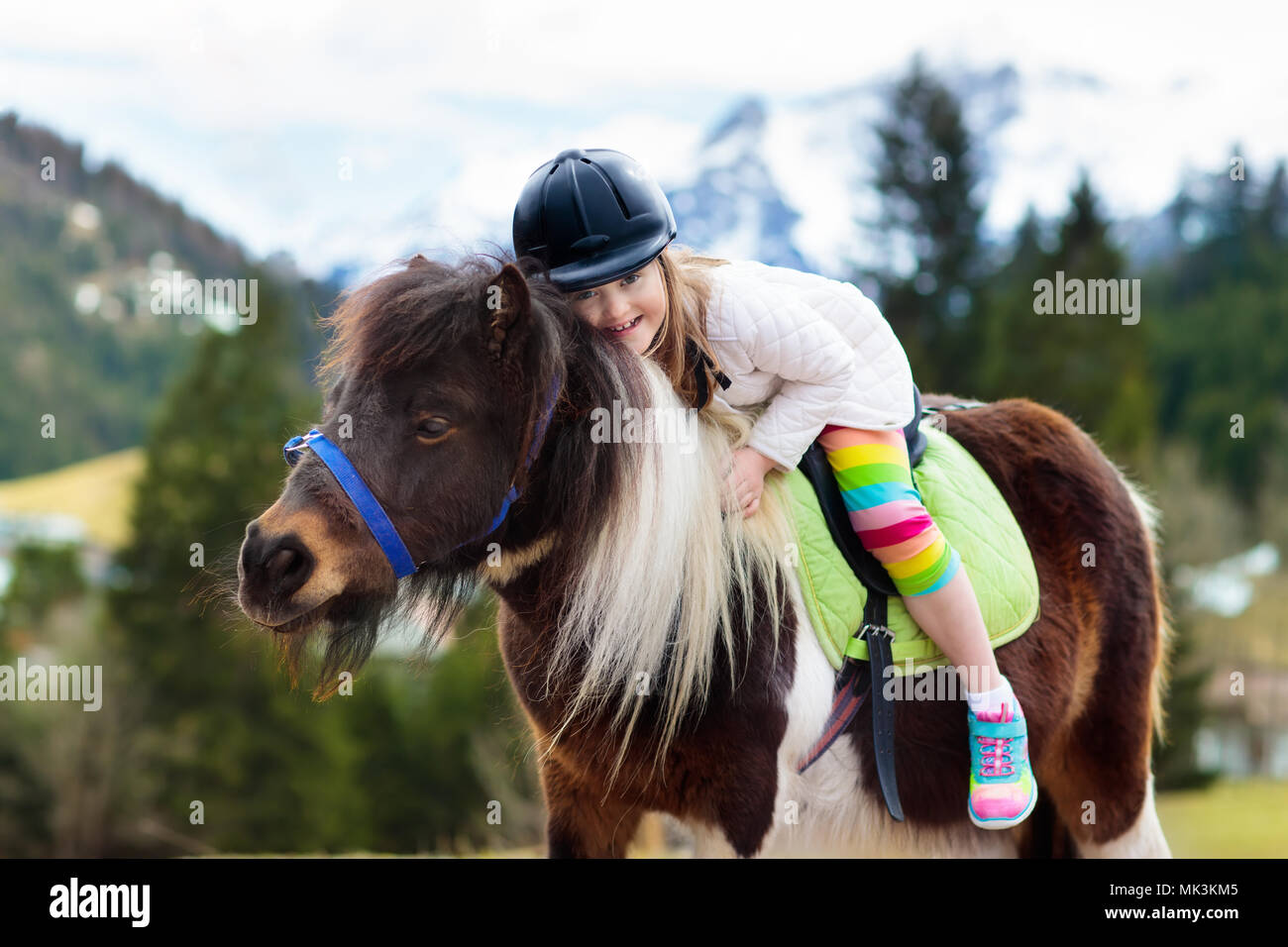Kids riding pony in the Alps mountains. Family spring vacation on horse ...
