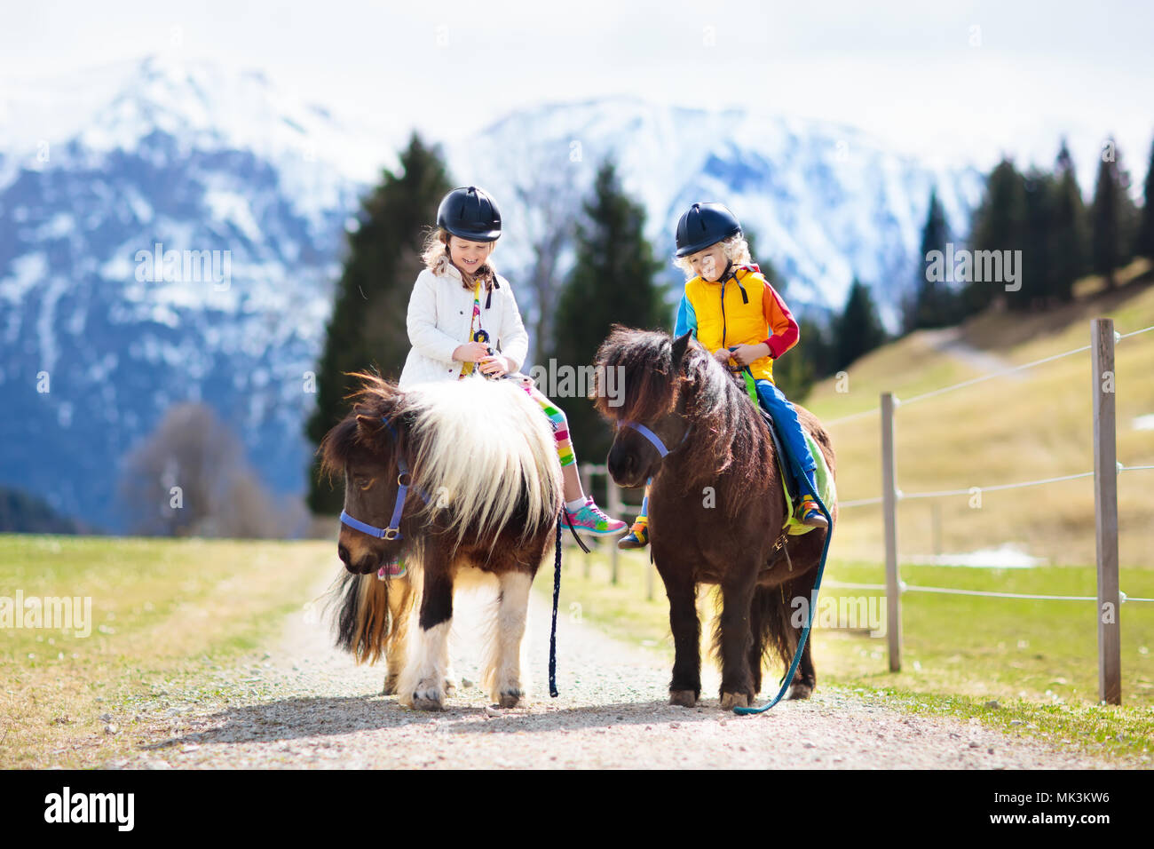 Kids riding pony in the Alps mountains. Family spring vacation on horse ...