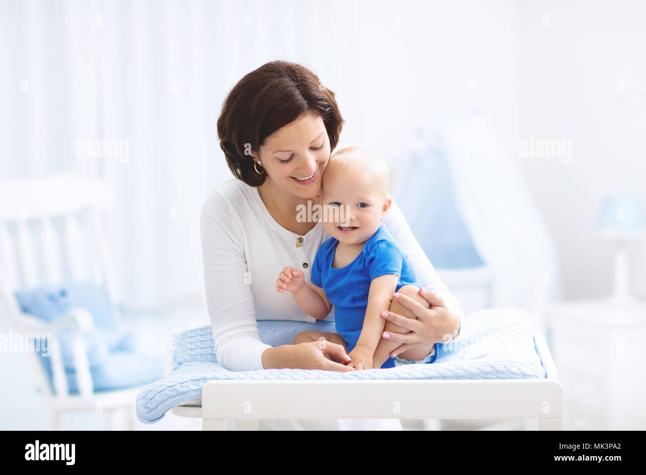 Mother and baby in diaper on changing table. Mom changing nappy on baby ...