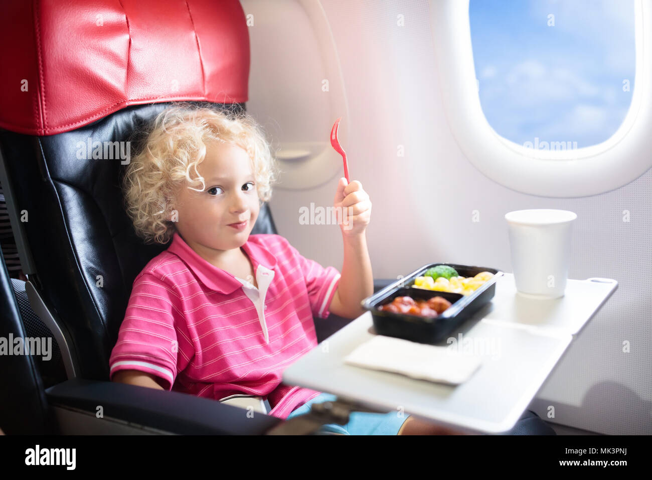 Child in airplane window seat. Kids flight meal. Children fly. Special ...