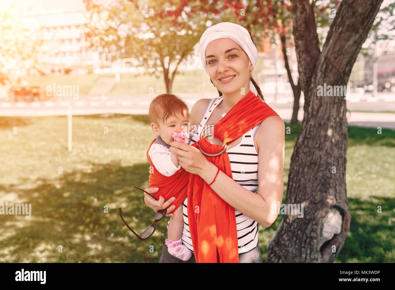 Mother carry a infant baby in wrap sling in park. Springtime. Concept ...