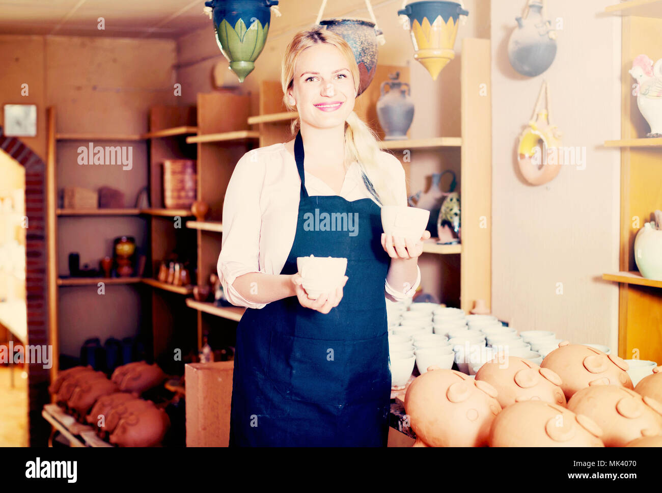 Portrait of efficient woman pottery worker with ceramic crockery in ...
